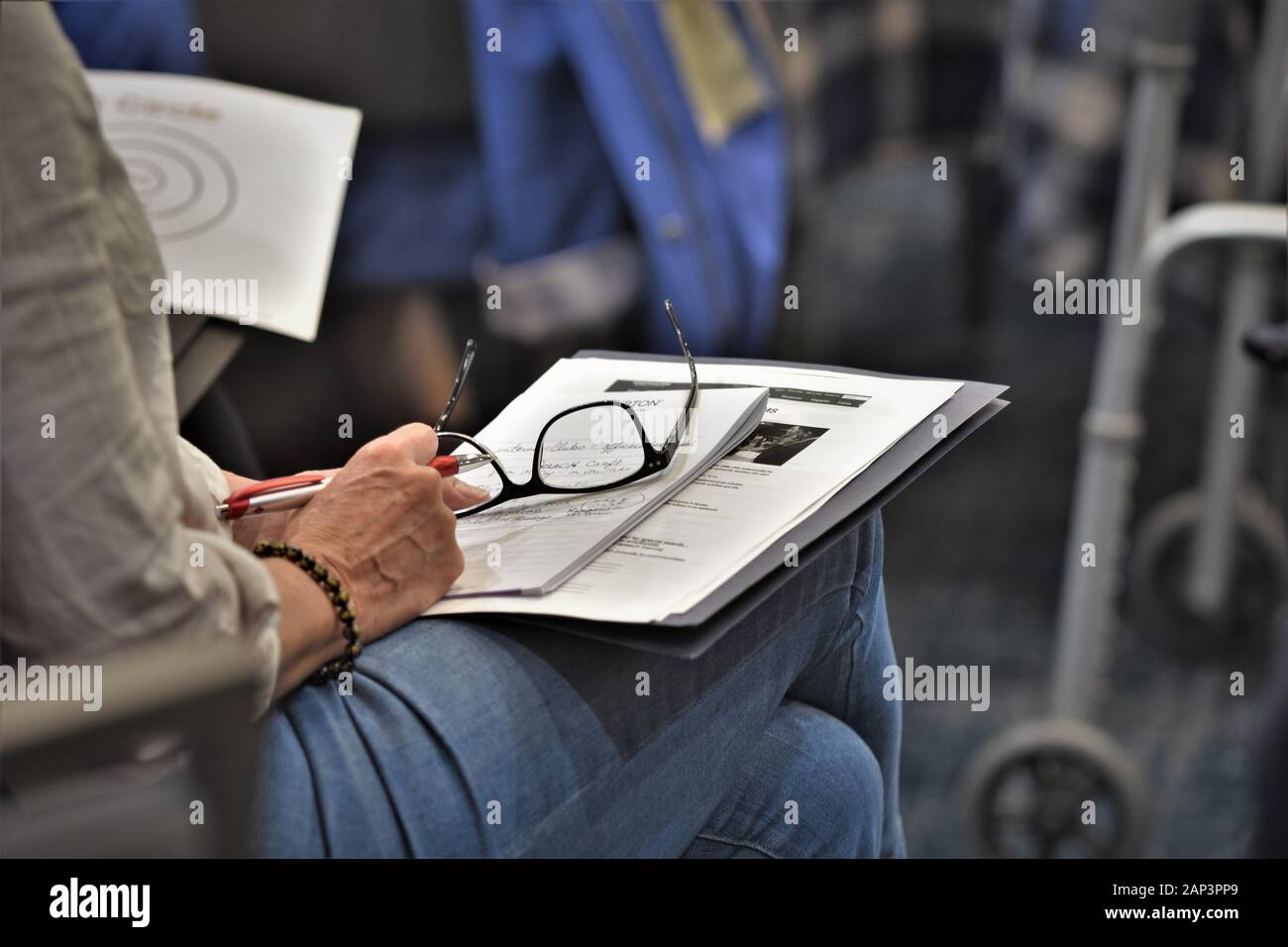Hands of a woman at a business meeting taking notes an holding glasses ...