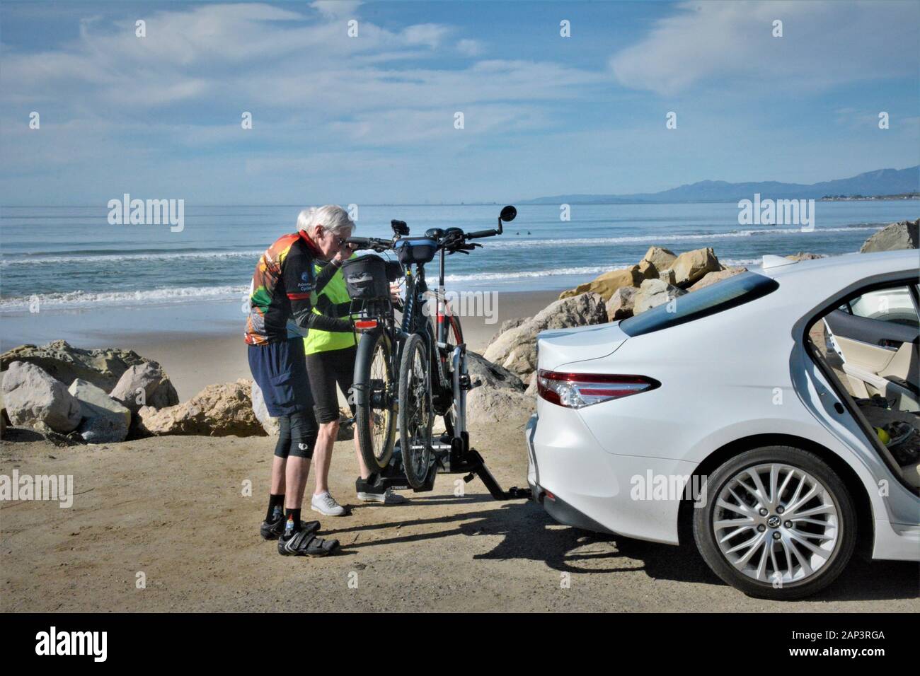 Senior man loading his bicycle on the rack on his car after workout on ...