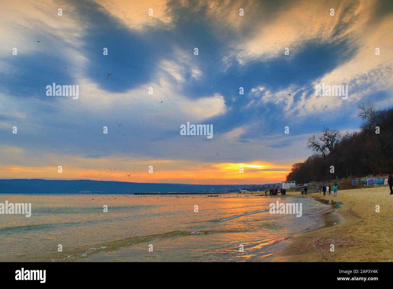 Picturesque clouds on a sunset skies over Varna bay and people walking ...