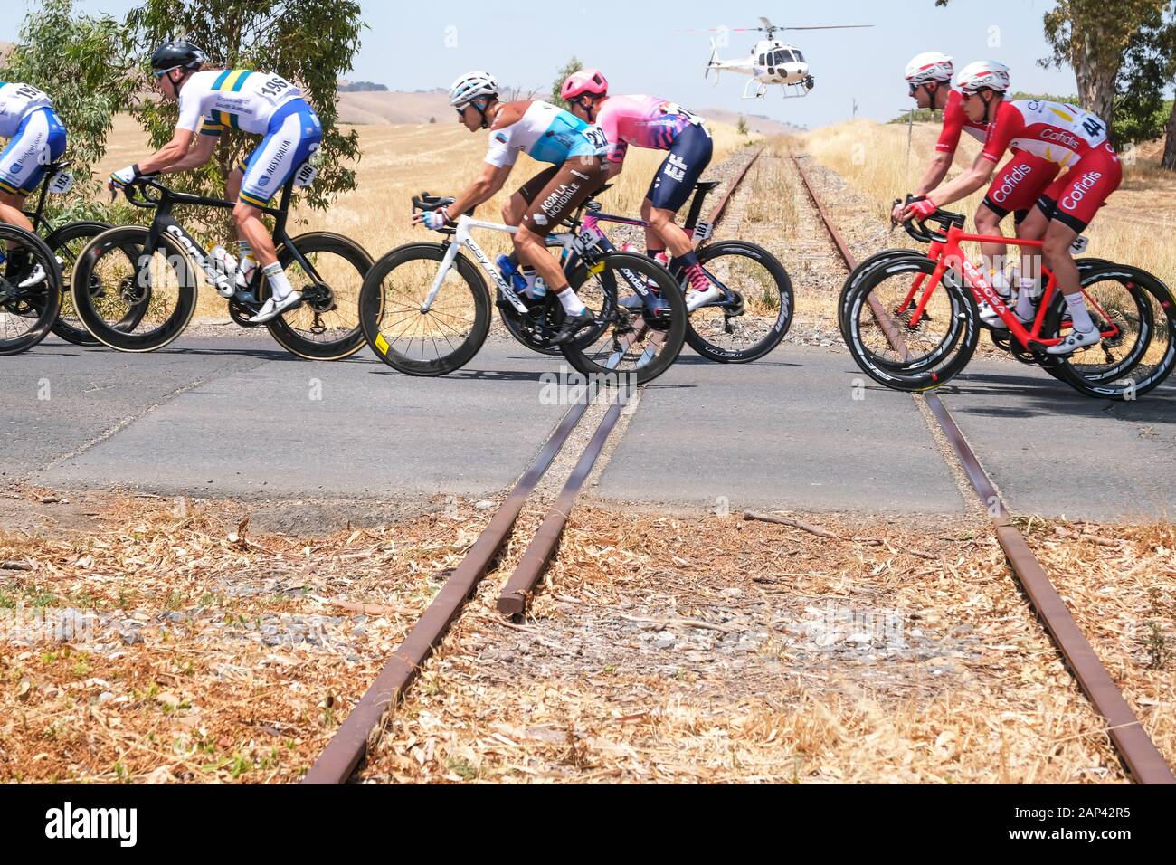 Riders on stage 1 of the 2020 Tour Down Under riding over a railway ...