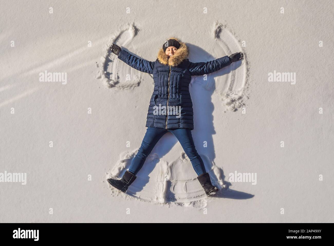 Portrait of a beautiful young woman laying down on a frozen snow lake ...