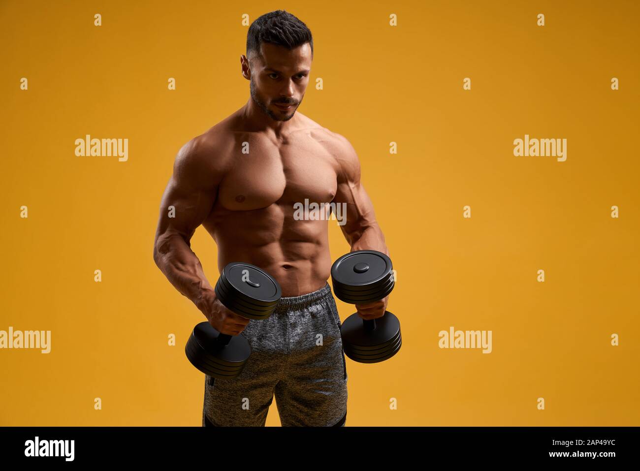 Front view of muscular young man with perfect abs working out with ...