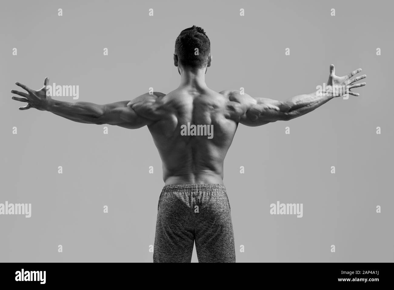 Back view of athletic shirtless guy demonstrating well trained body ...