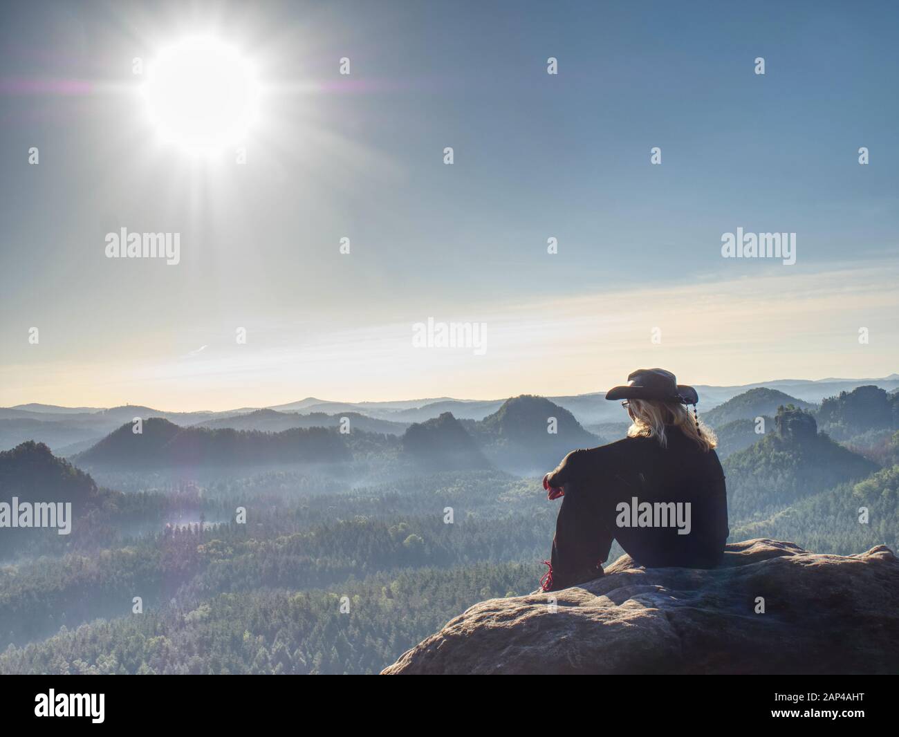 Attractive woman wearing a straw cowboy hat is sit in front of large ...