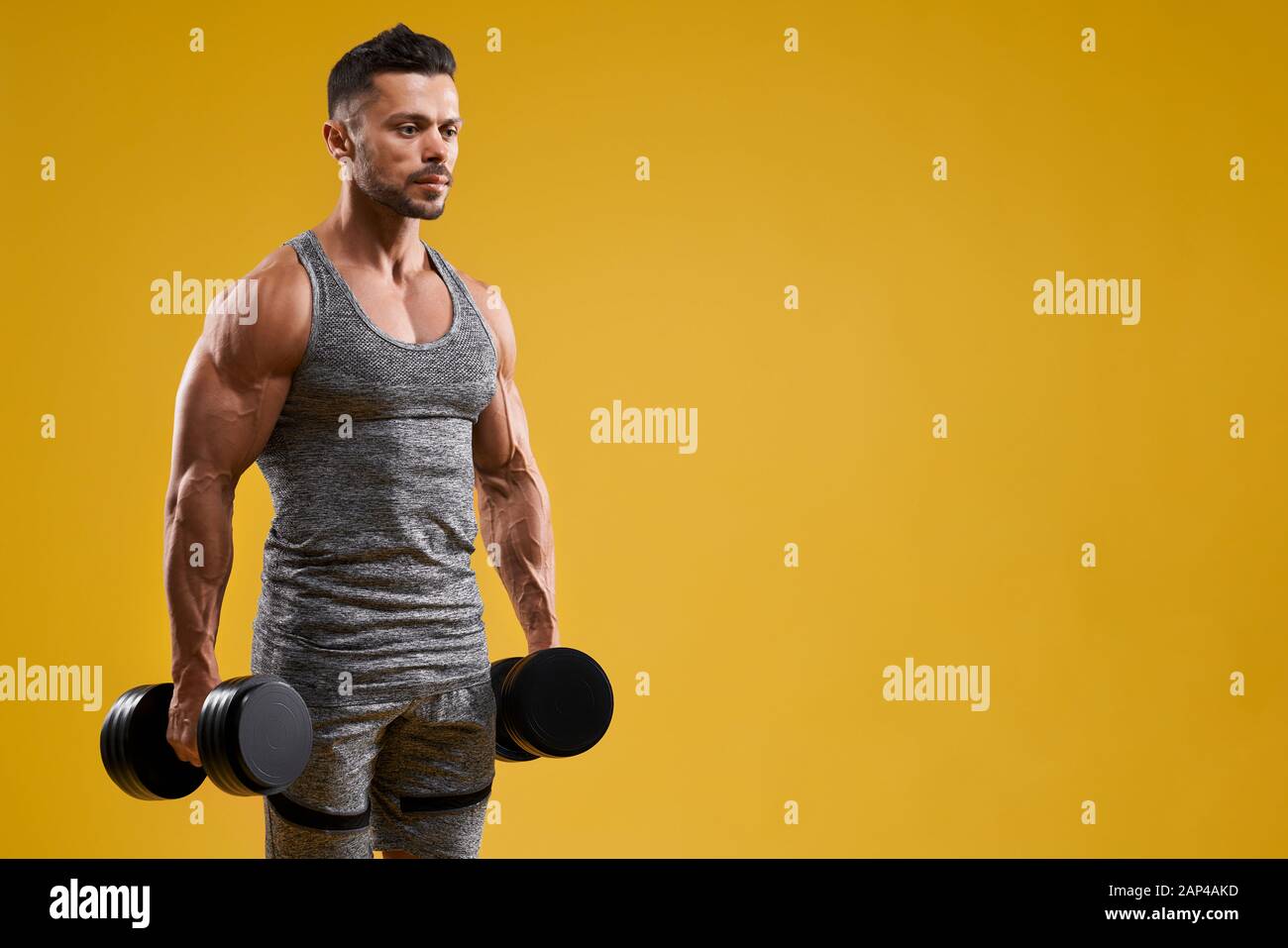Side view of strong muscular gentleman doing exercise with dumbbells ...