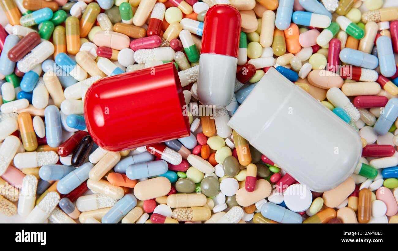 Large capsule lies open on many different colored medicines drugs Stock ...