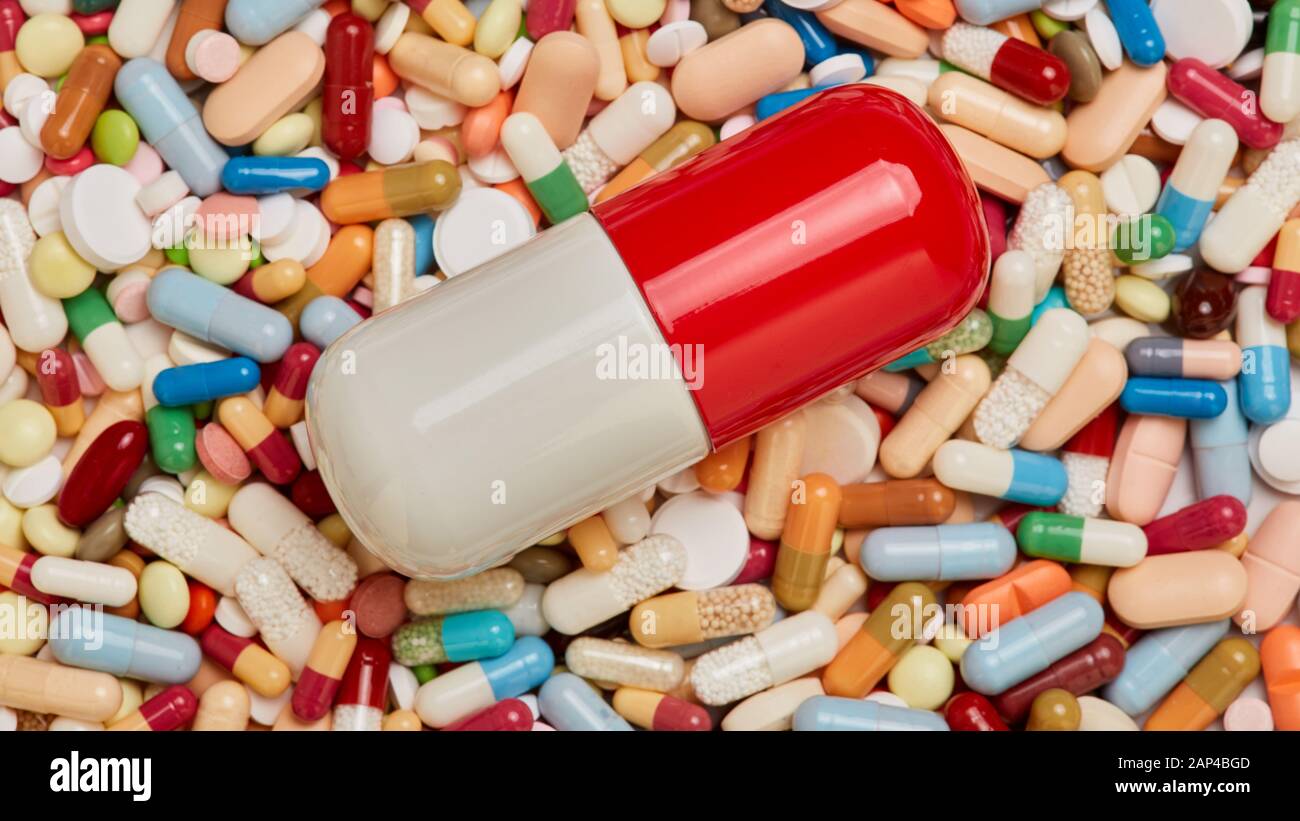 Colorful big capsule lies on small medicines drugs and tablets Stock ...