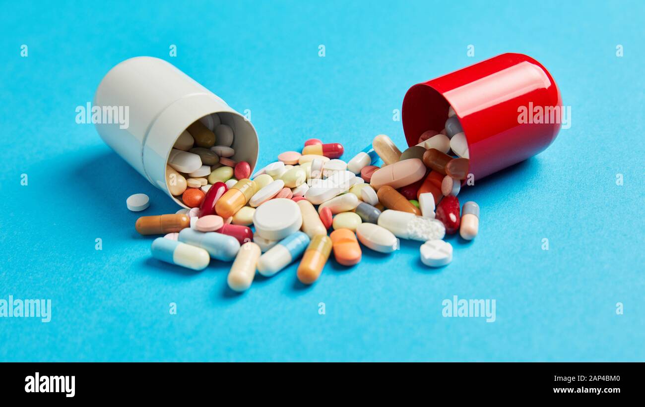Colorful medicines drugs in large capsule on a blue background Stock ...