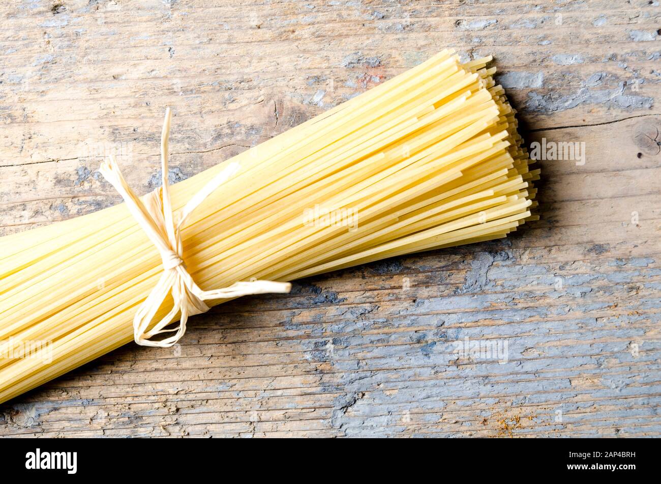 Italian raw pasta on rustic wooden table from above. Traditional long ...