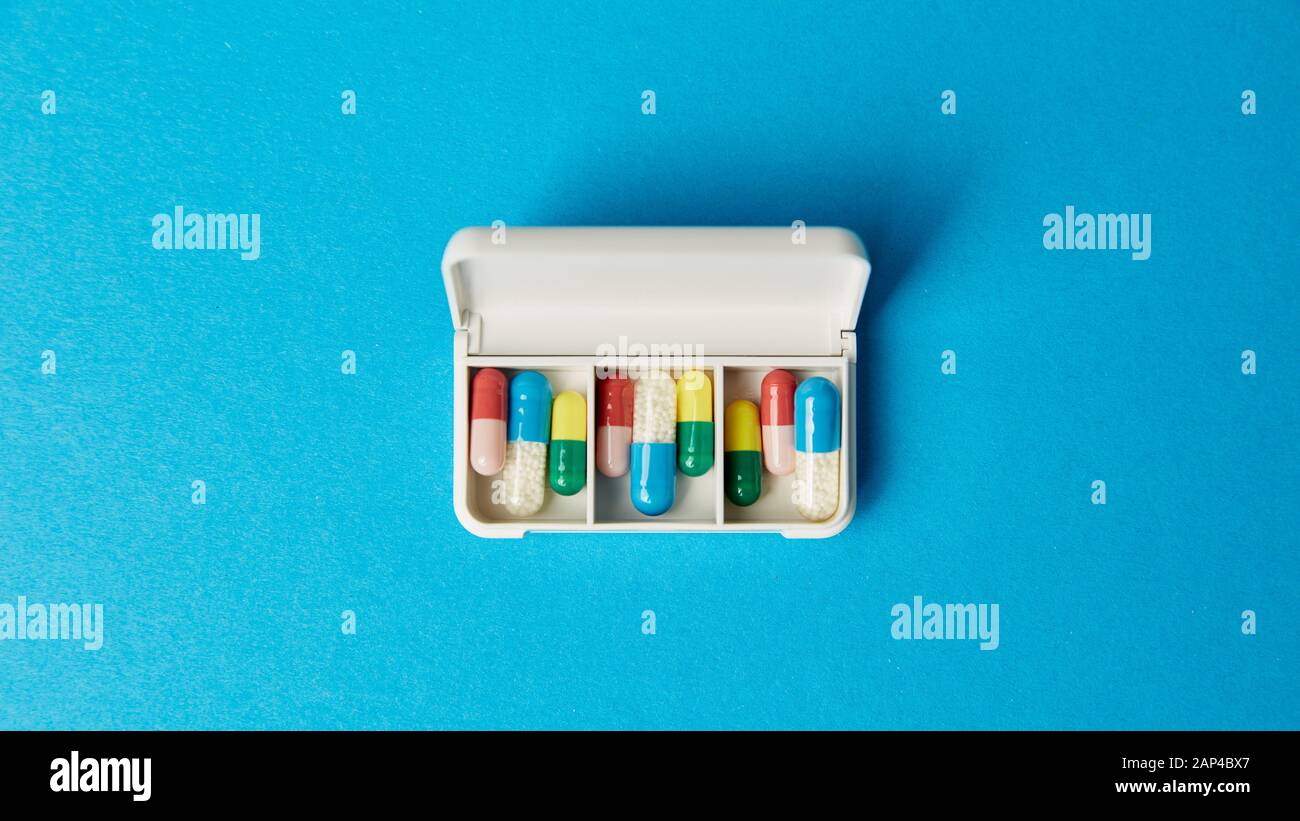 Open pill box with lots of medication on a blue background Stock Photo ...