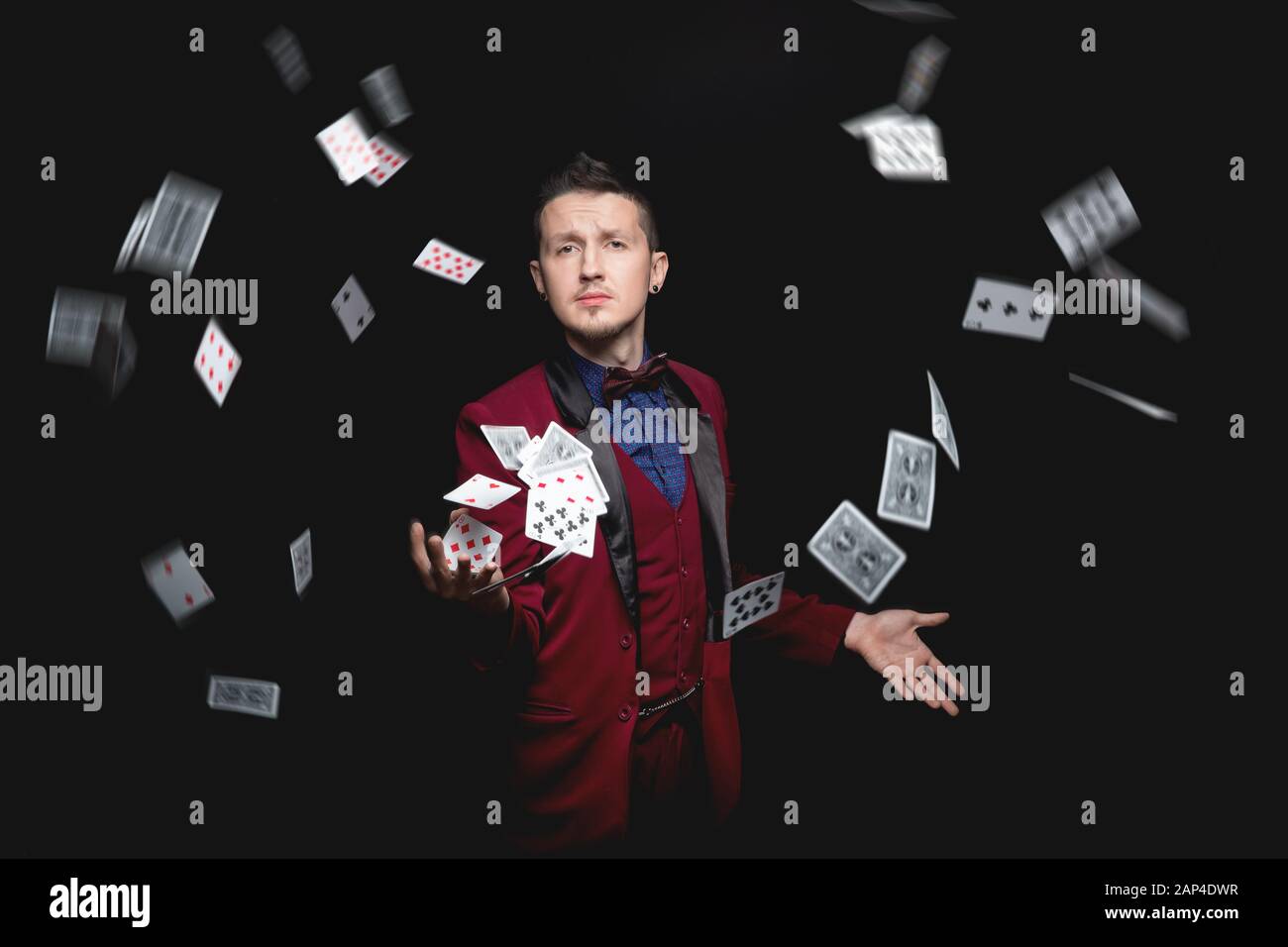 Illusionist magician man shows magic with playing cards on black ...