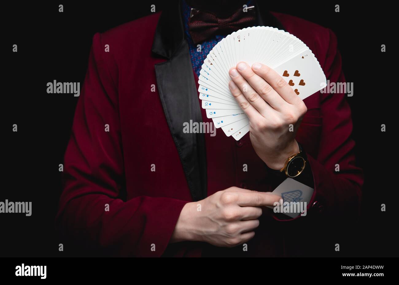 Illusionist man shows fan of playing cards takes ace out hand on black ...