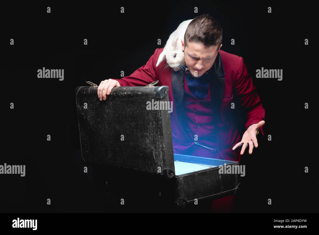 Magician shows trick with disappearance white rabbit in suitcase magic ...