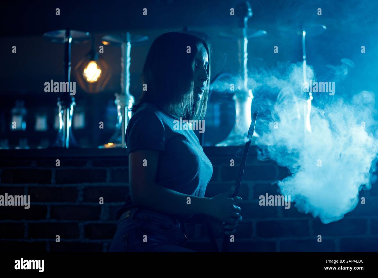Beautiful woman in night club smoke hookah or shisha bar, blue ...