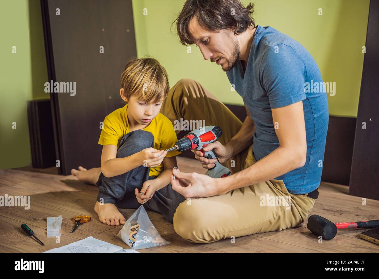 Father and son assembling furniture. Boy helping his dad at home. Happy ...