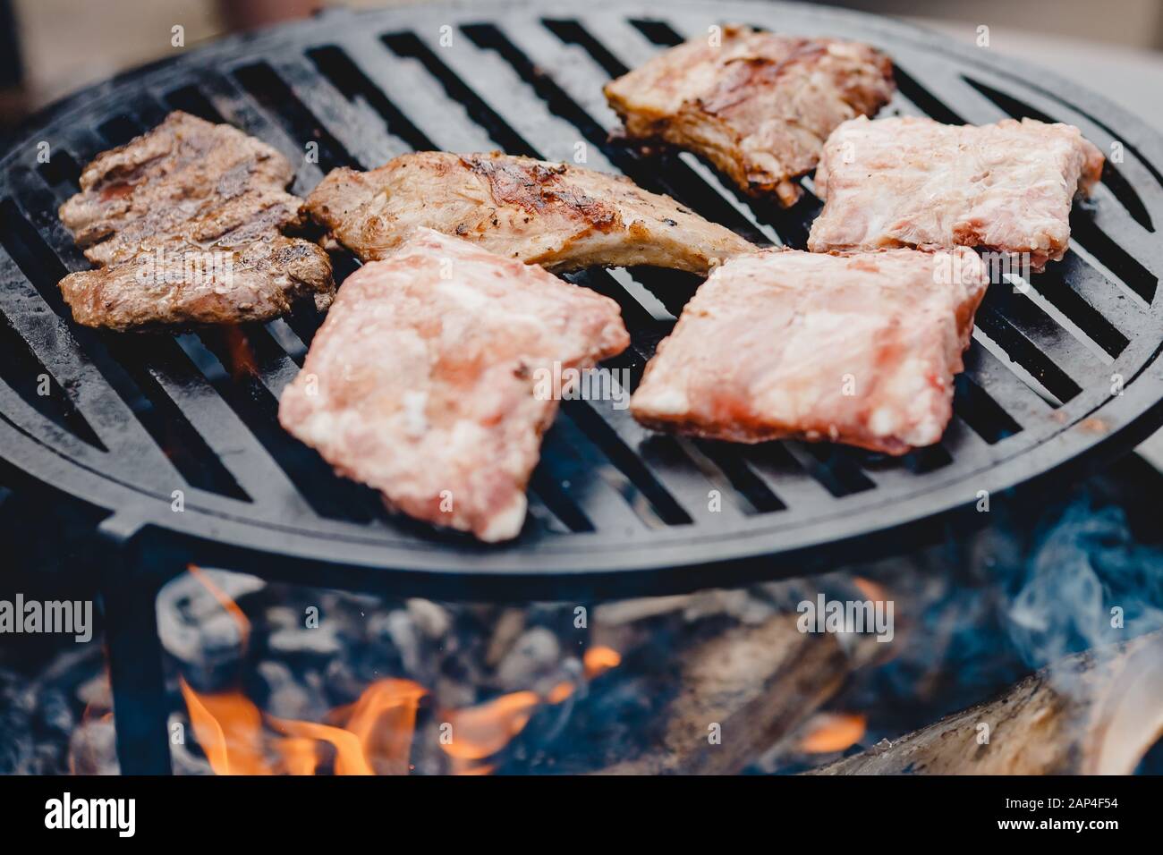 Pork ribs and steak cooked on grill, open fire street food festival ...