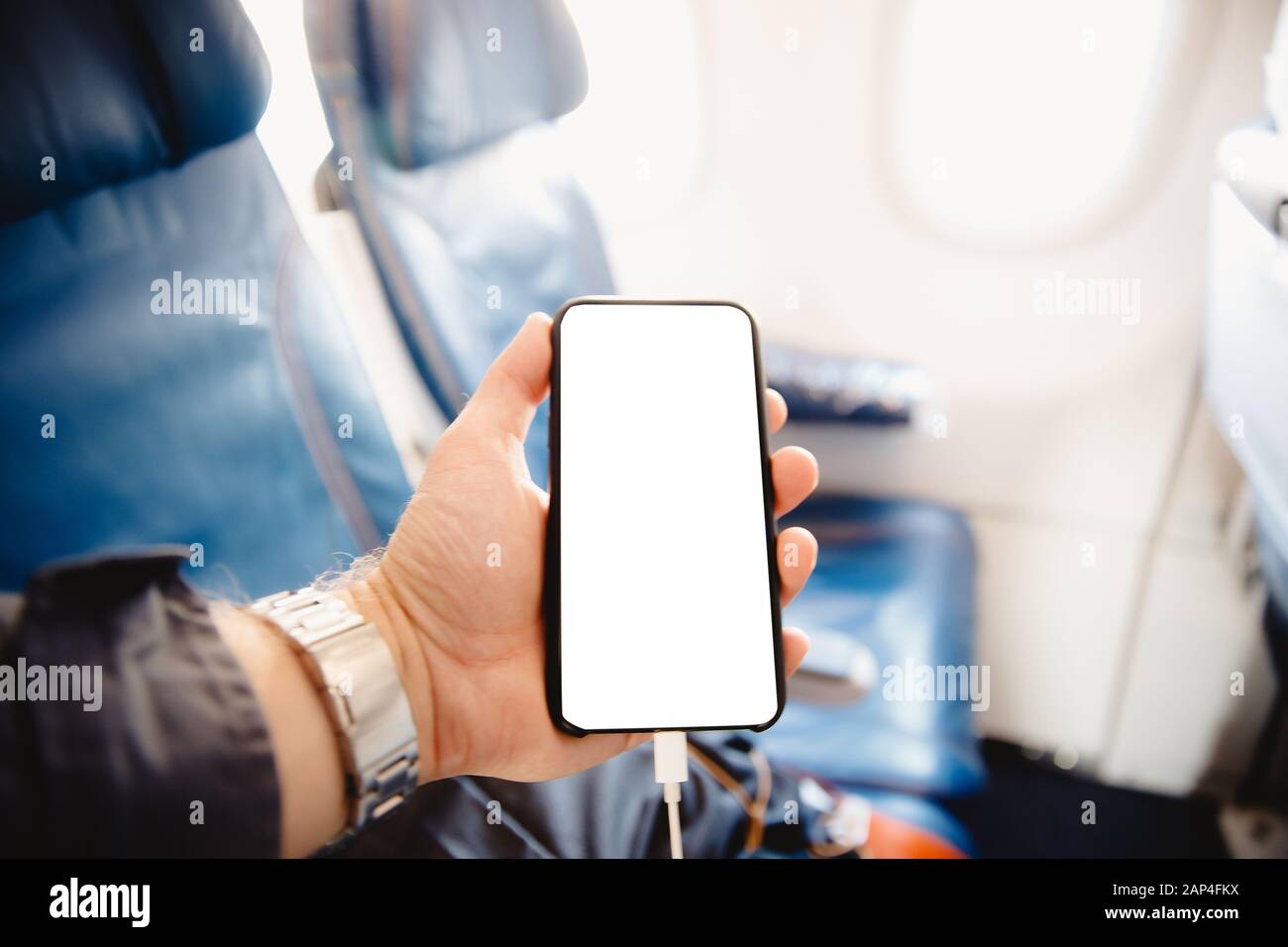 White screen mobile phone in cockpit of plane against background seats ...
