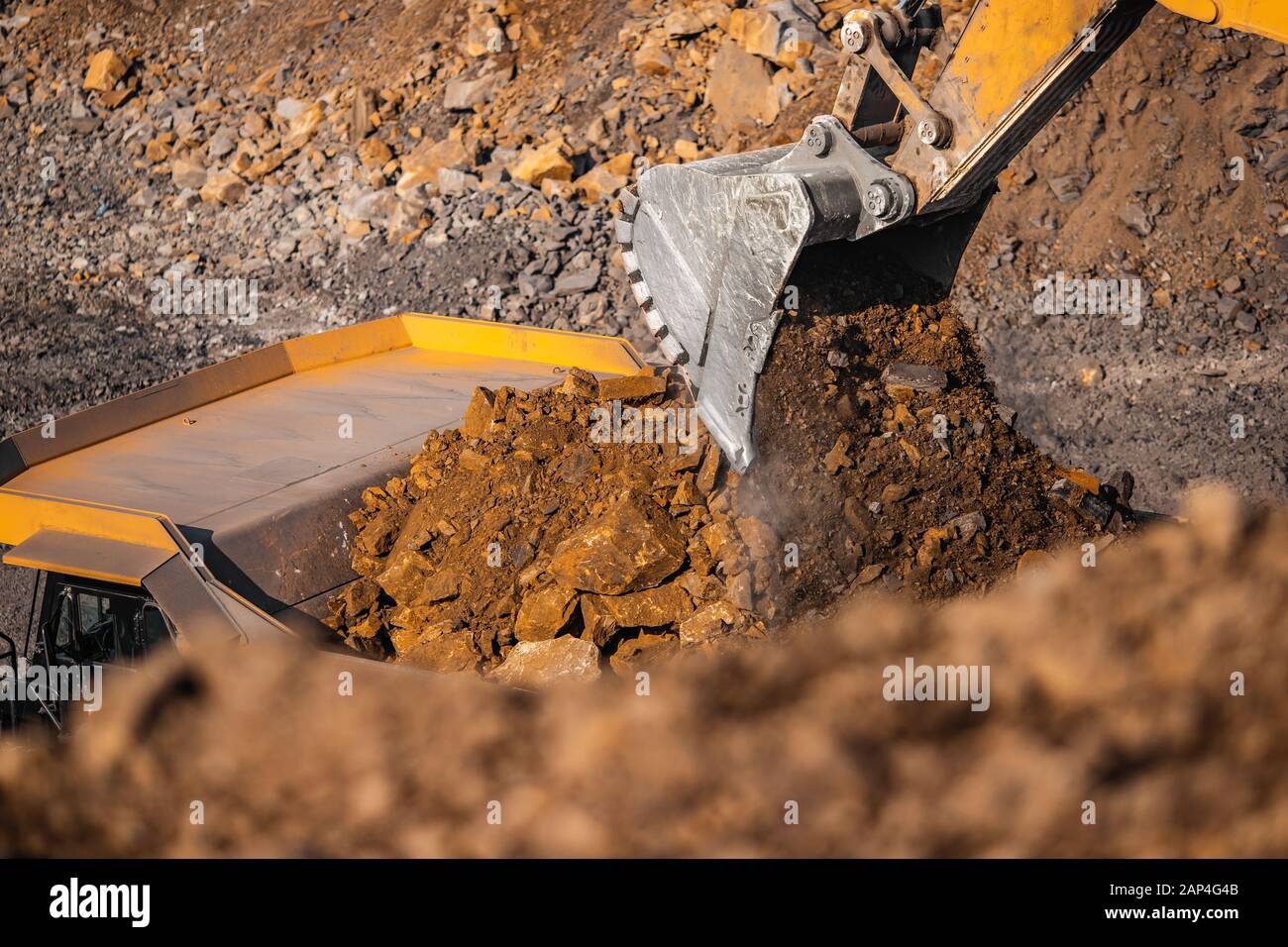 Gold ore mining, loading excavator bucket into body of mine truck Stock ...