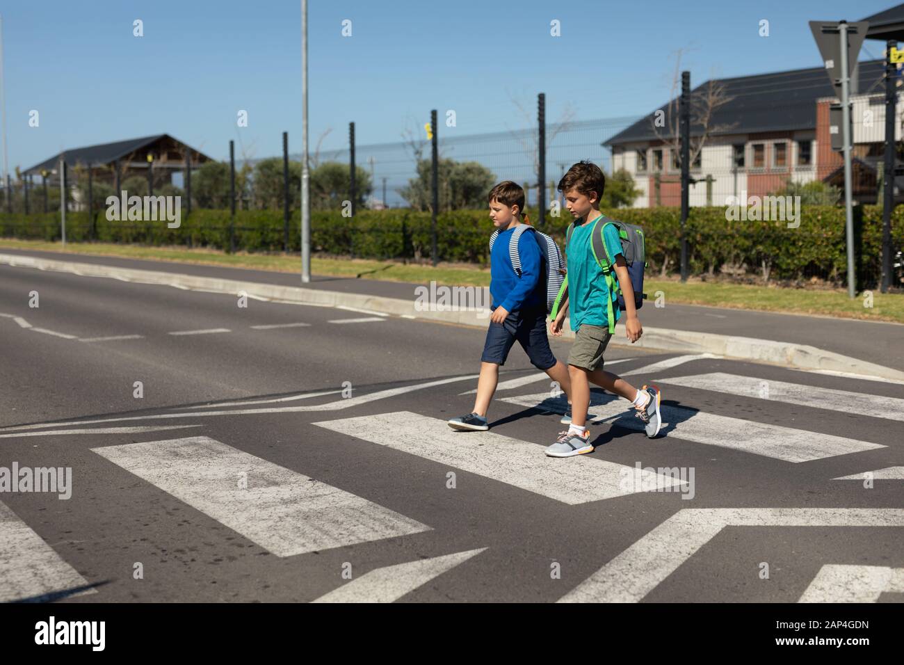 Two schoolboys crossing the road on a pedestrian crossing Stock Photo ...