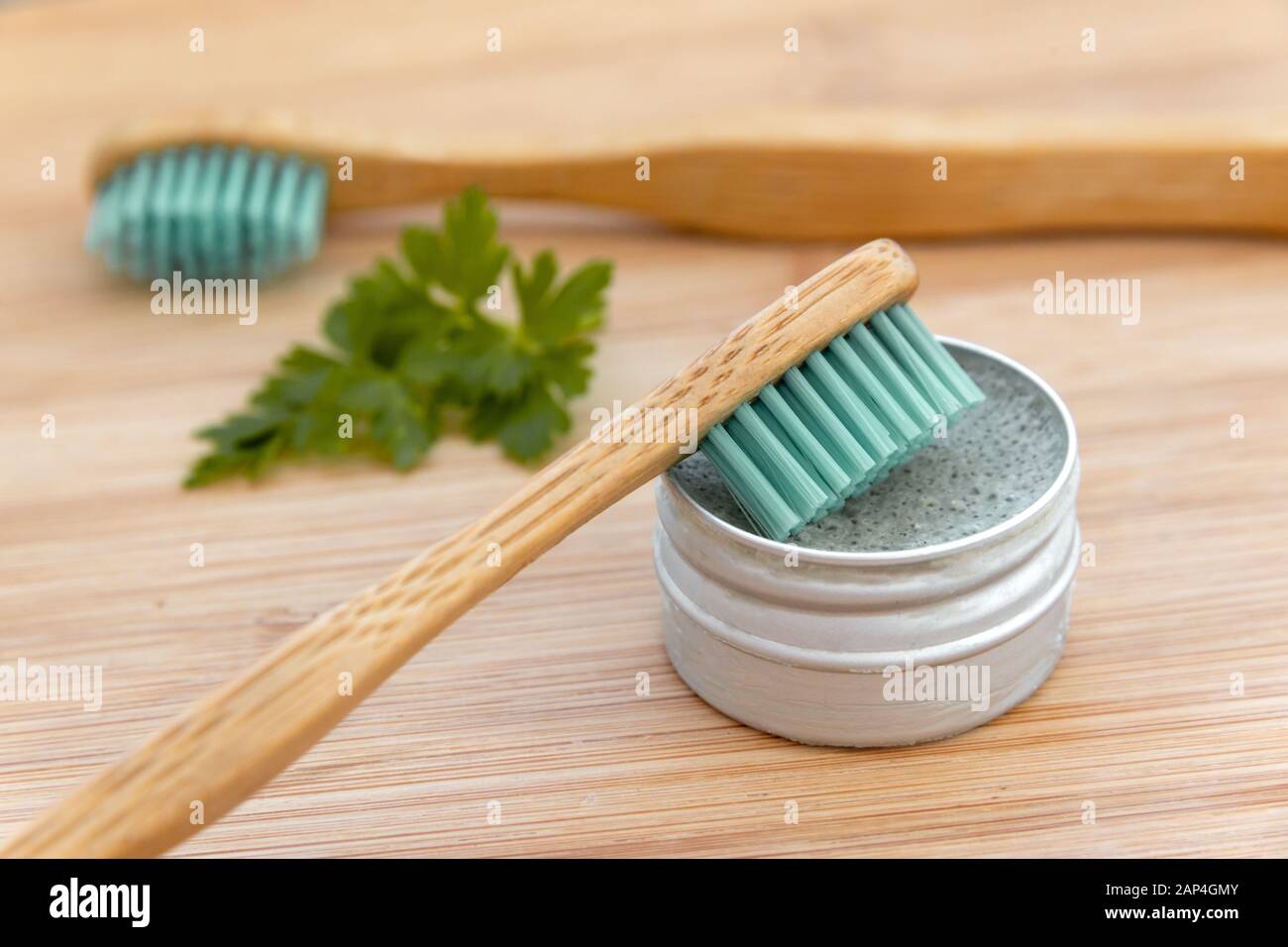 Bamboo toothbrushes and solid toothpaste in metal tin on wood ...