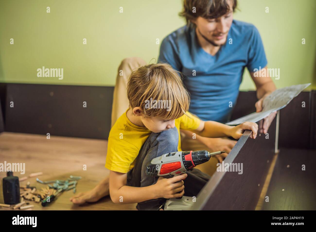 Father and son assembling furniture. Boy helping his dad at home. Happy ...