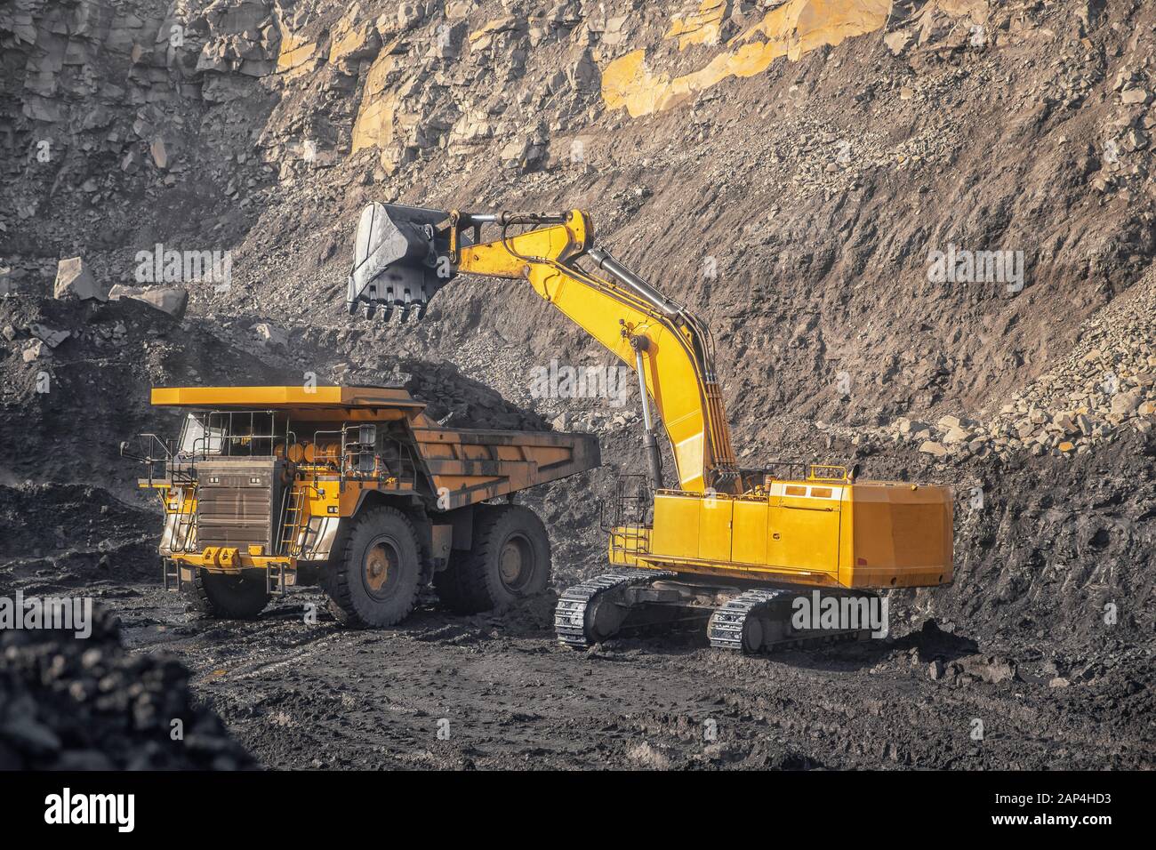 Open pit mine industry, excavator loading coal on big yellow mining ...