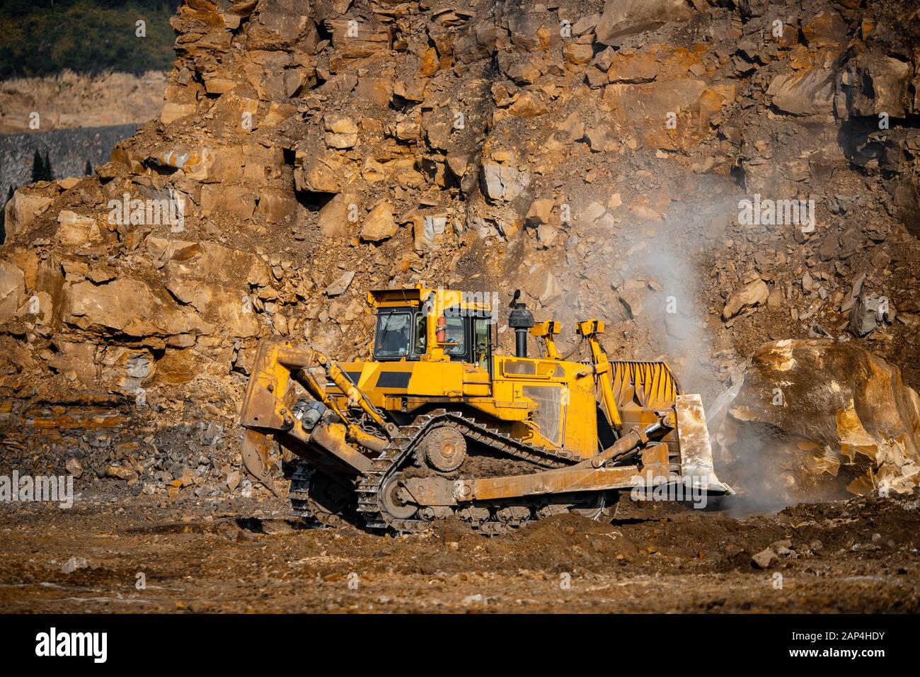 Grader excavator removes large stones after rock explosion blasting ...