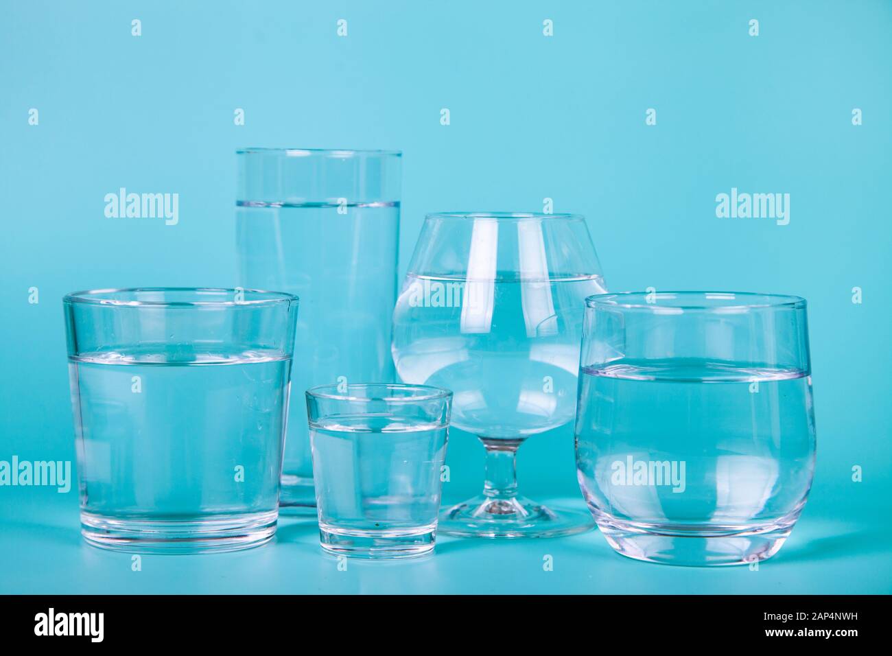 Glasses of different shapes with water on a blue background Stock Photo ...