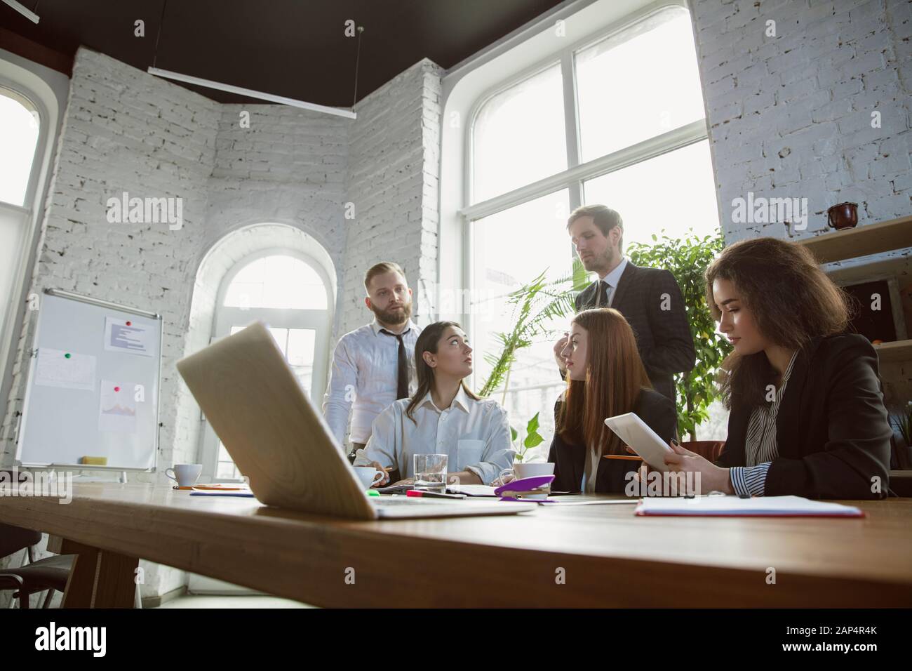 Positive. Group of young business professionals having a meeting ...