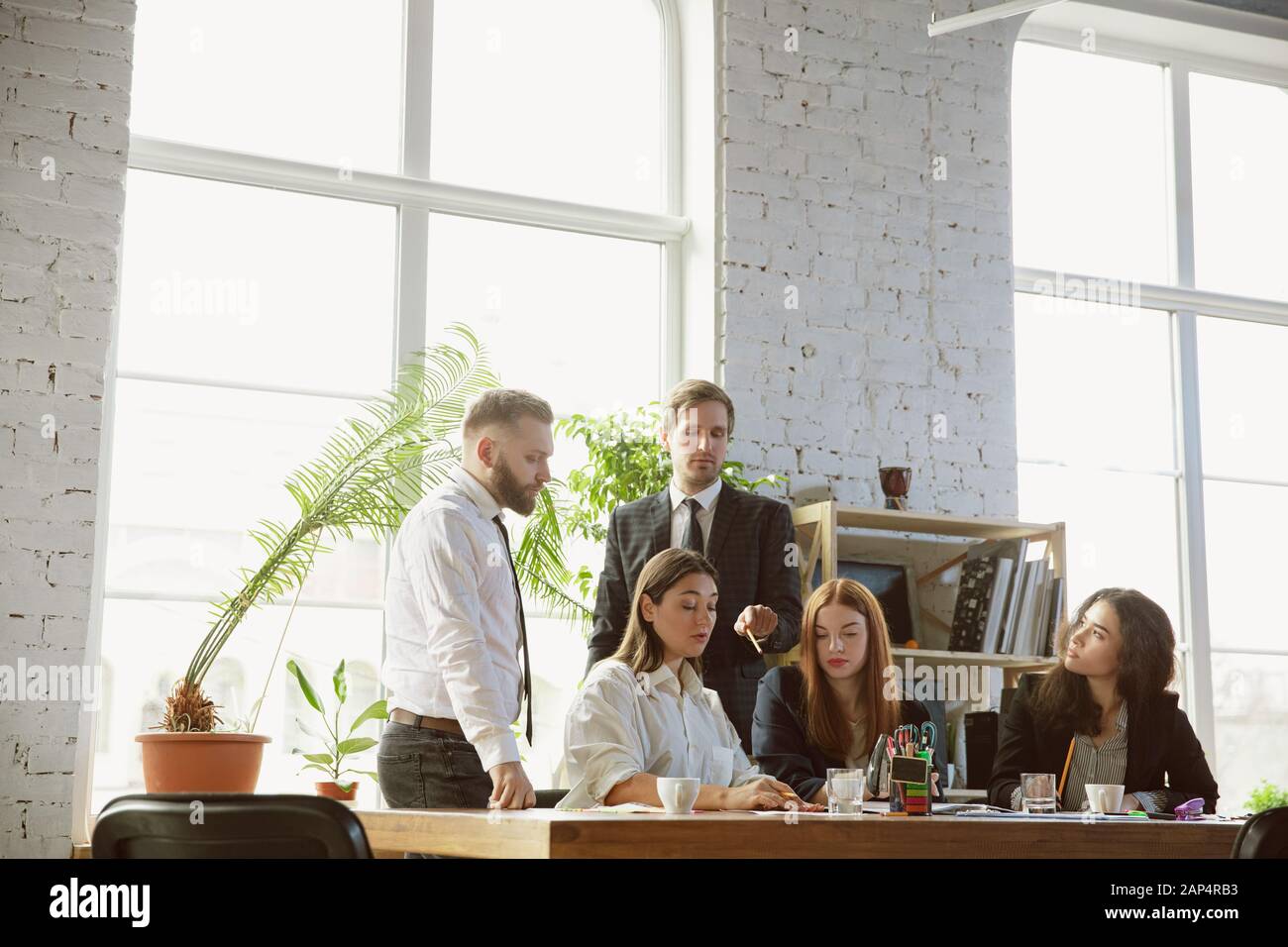 Positive. Group of young business professionals having a meeting ...