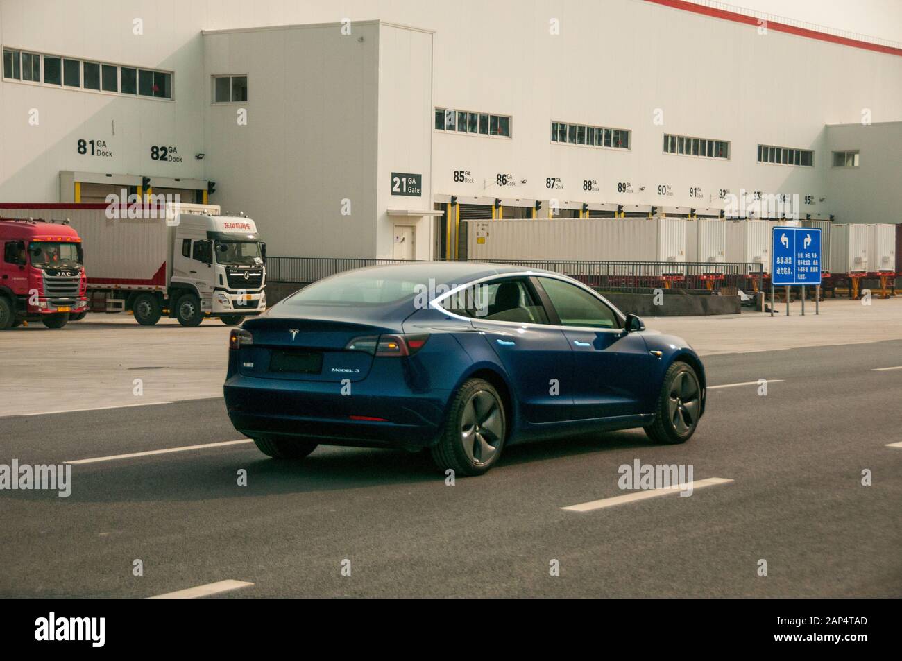 A Chinese made Tesla Model 3 driving past the new Tesla factory in ...