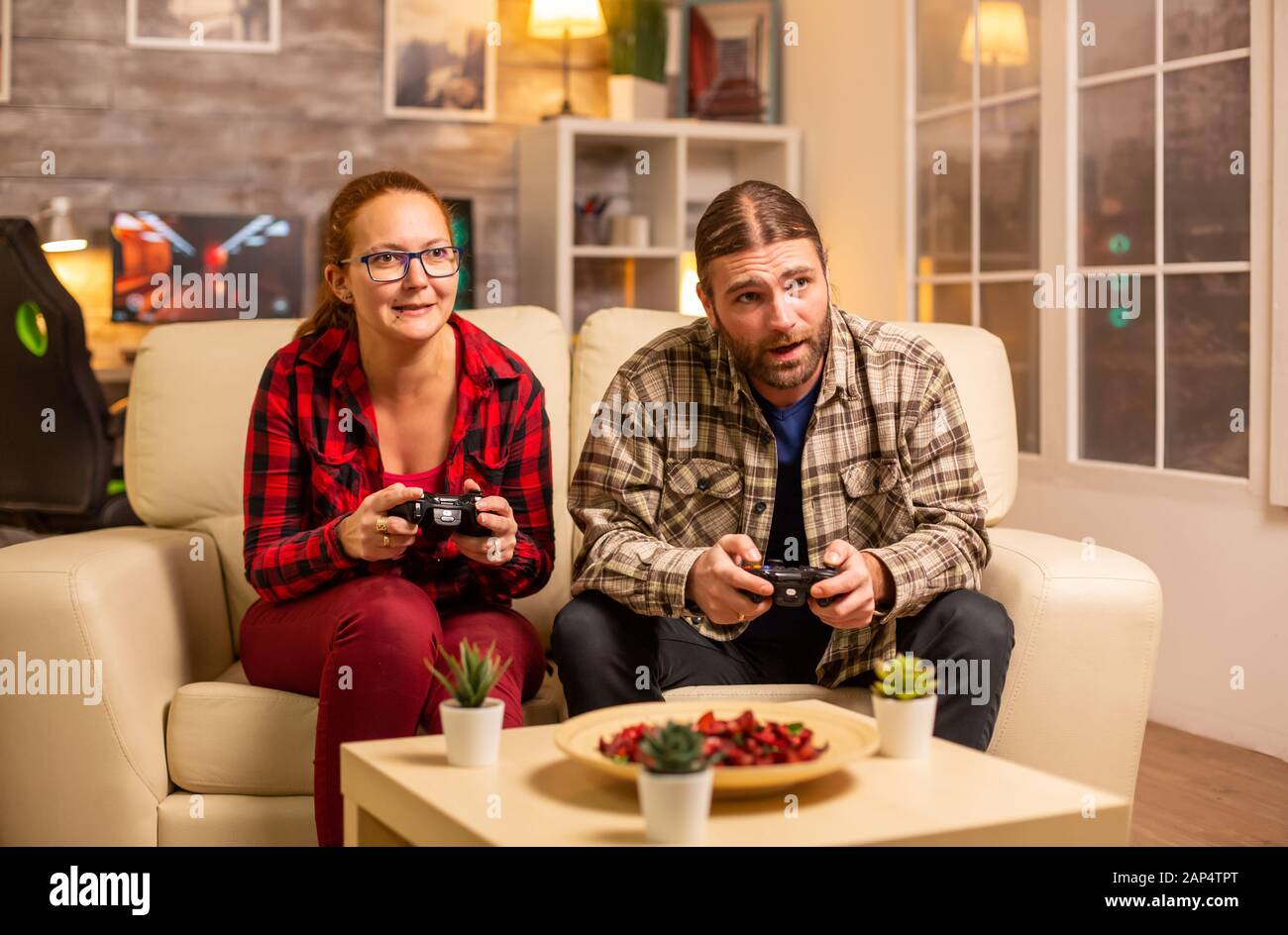Gamers couple playing video games on the TV with wireless controllers ...