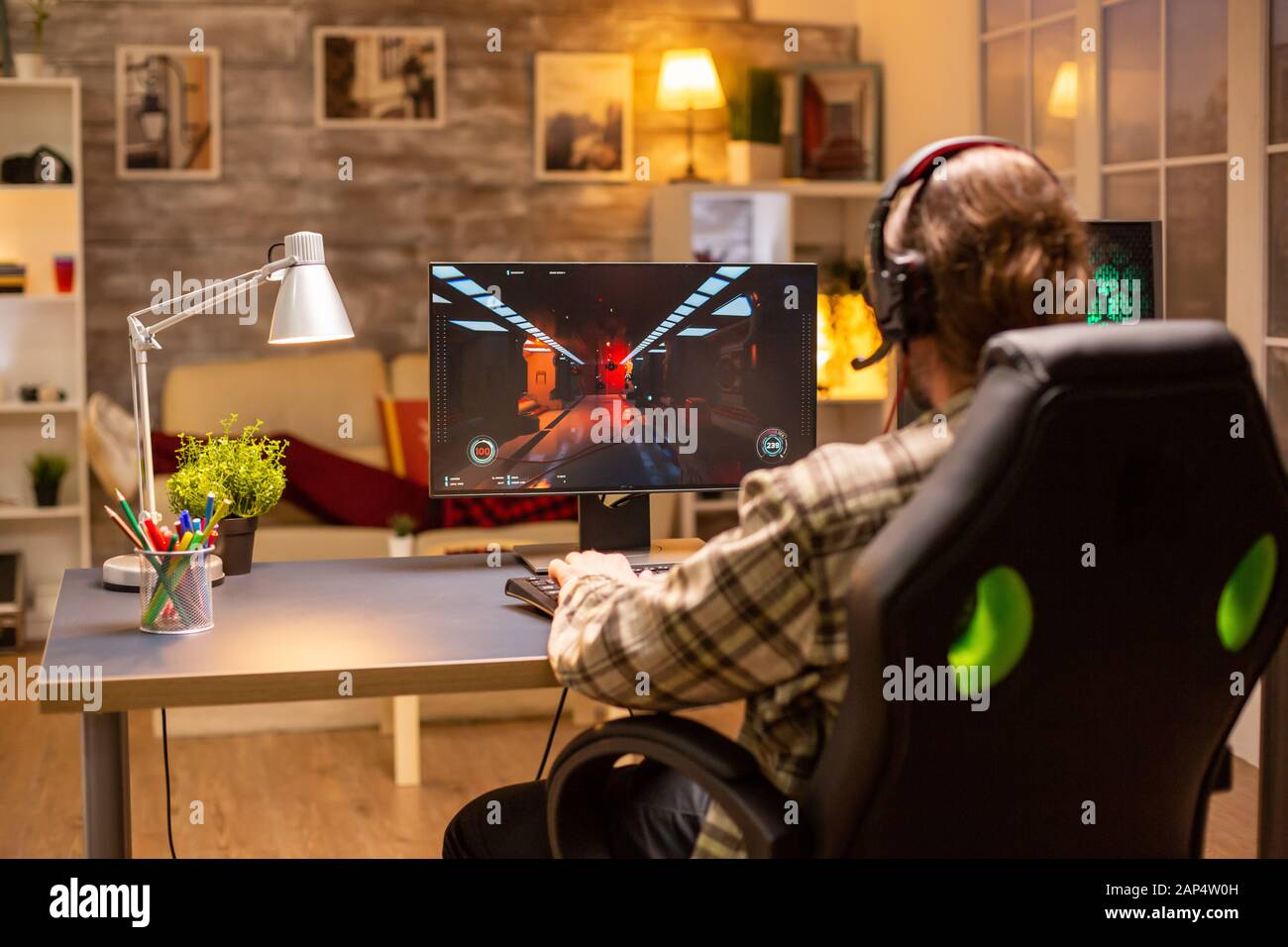 Back view of gamer male playing a shooter on his powerful PC computer ...