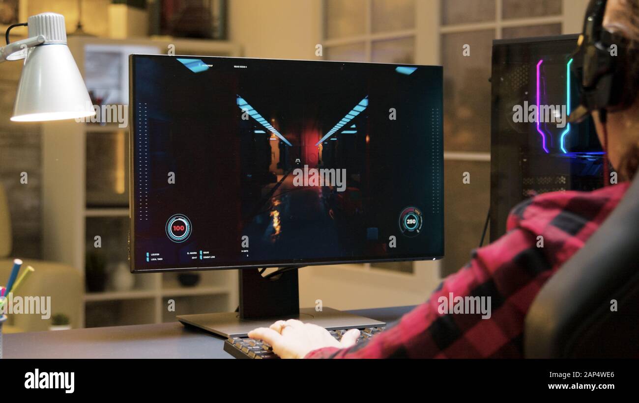 Female gamer with headphones playing shooter games on computer and ...