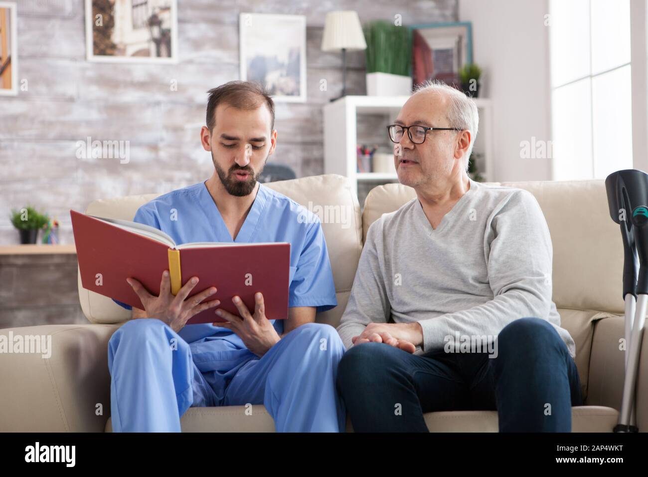 Male doctor reading a book for elderly age male in nursing home Stock ...