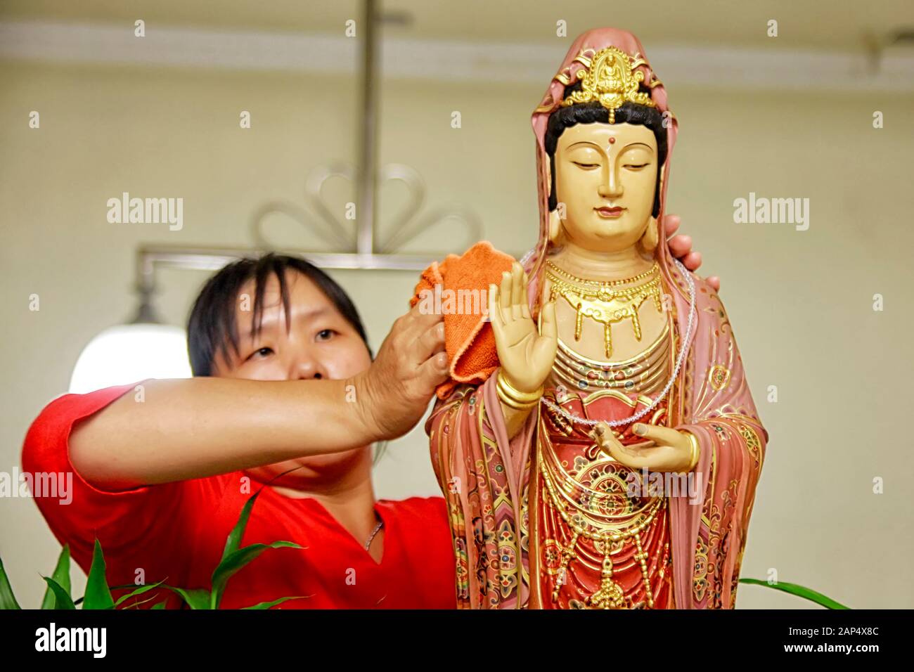 A woman cleans a buddhas statue during the celebration at Sakyamuni ...