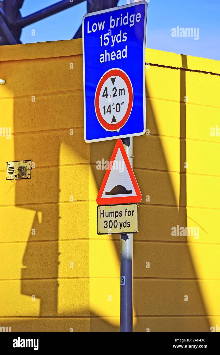 Road traffic sign casting shadow on bright yellow wall of building ...