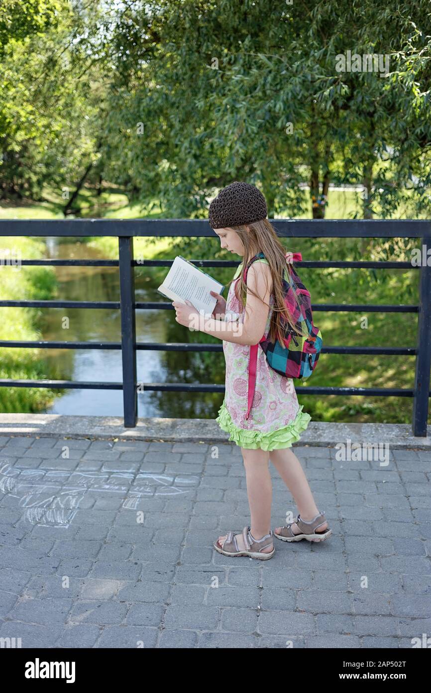 Girl reading a book while walking across the bridge Stock Photo - Alamy