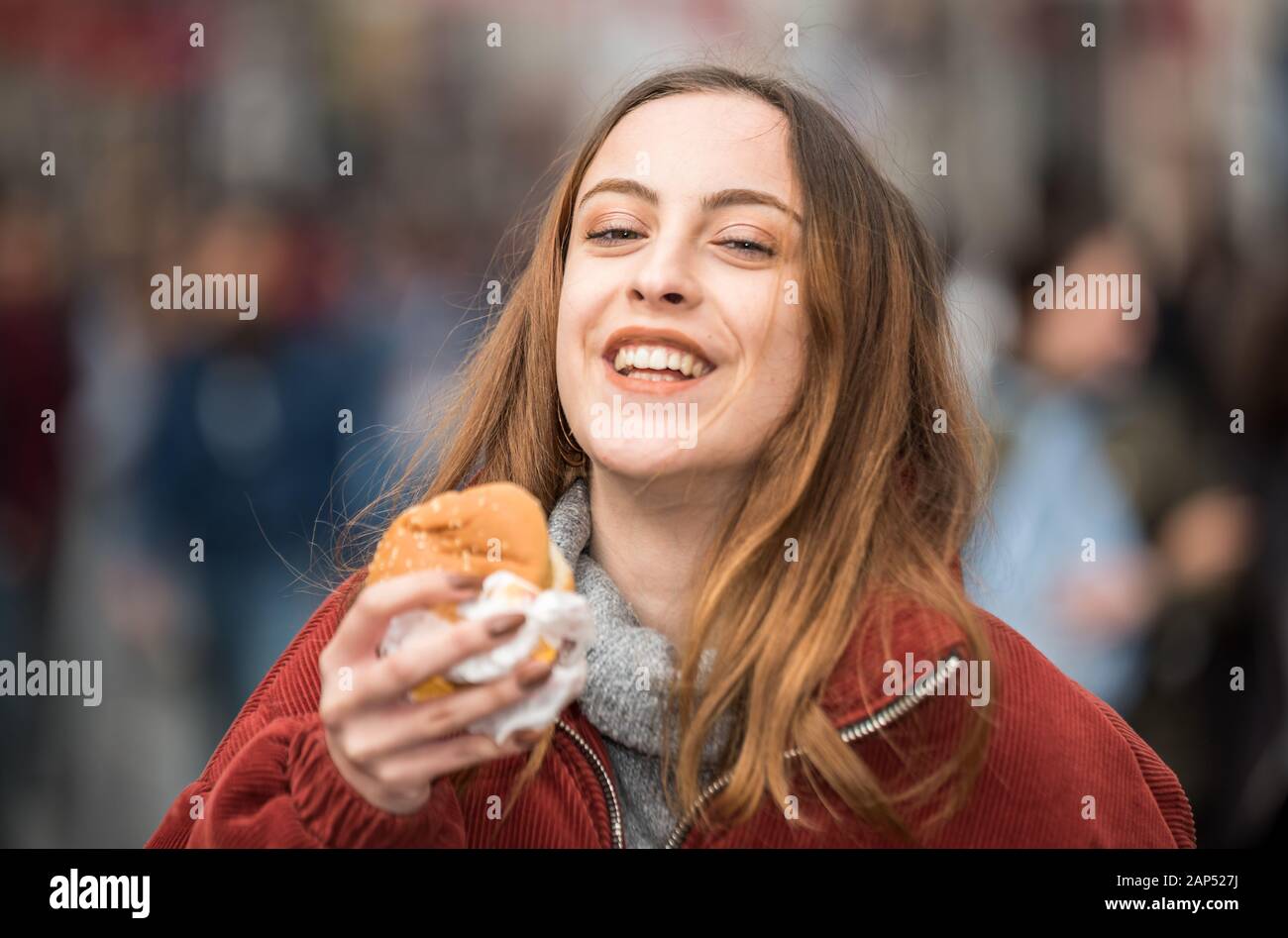 Beautiful young cute girl in fashionable clothes enjoys fast food ...