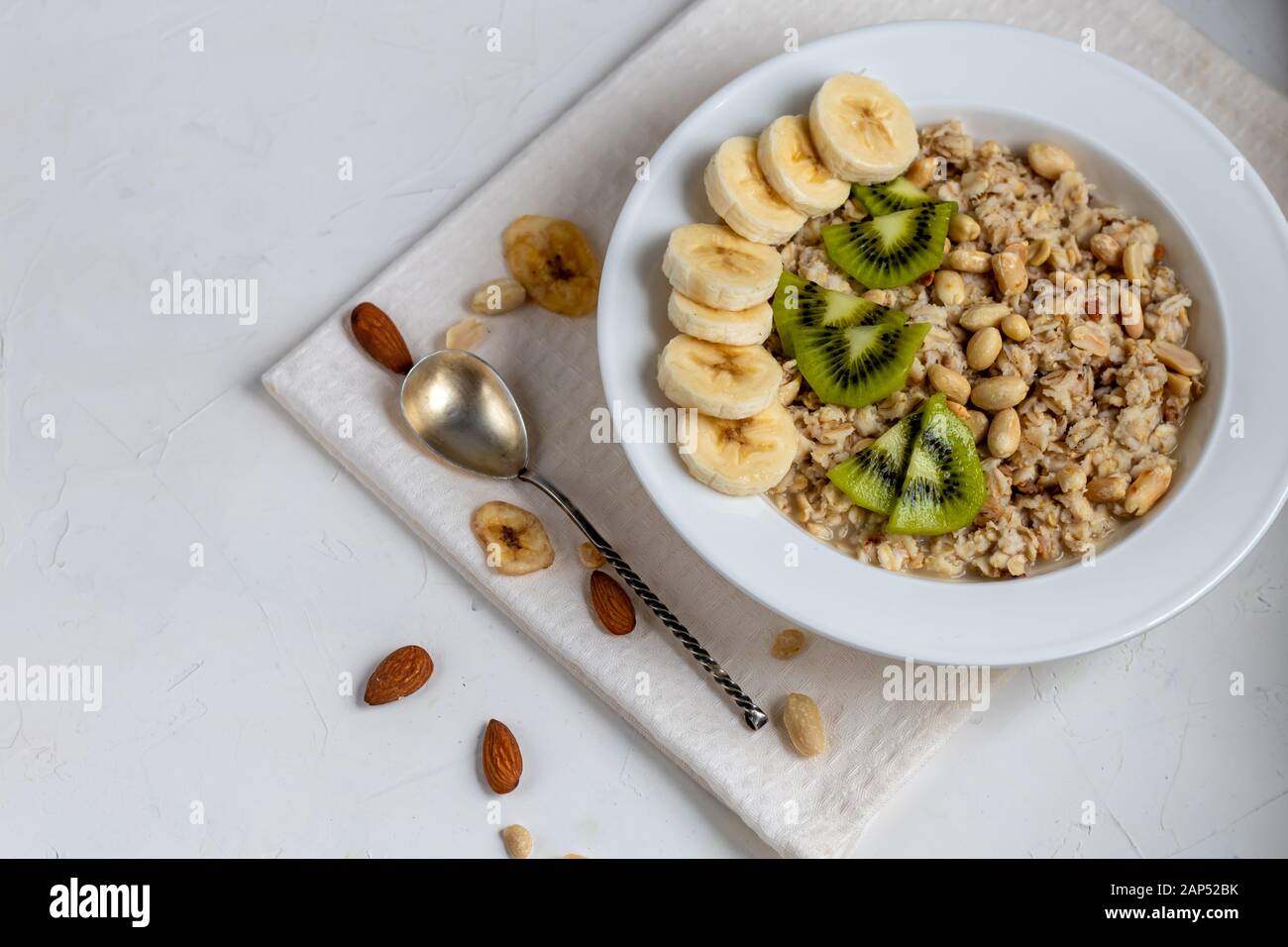 Breakfast consisting of oatmeal, nuts and fruits. Kiwi, banana ...
