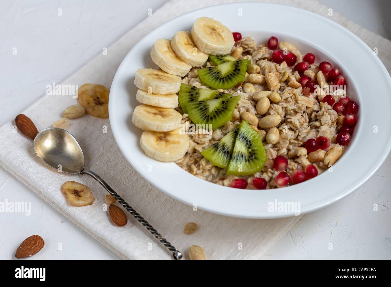Breakfast consisting of oatmeal, nuts and fruits. Kiwi, banana ...