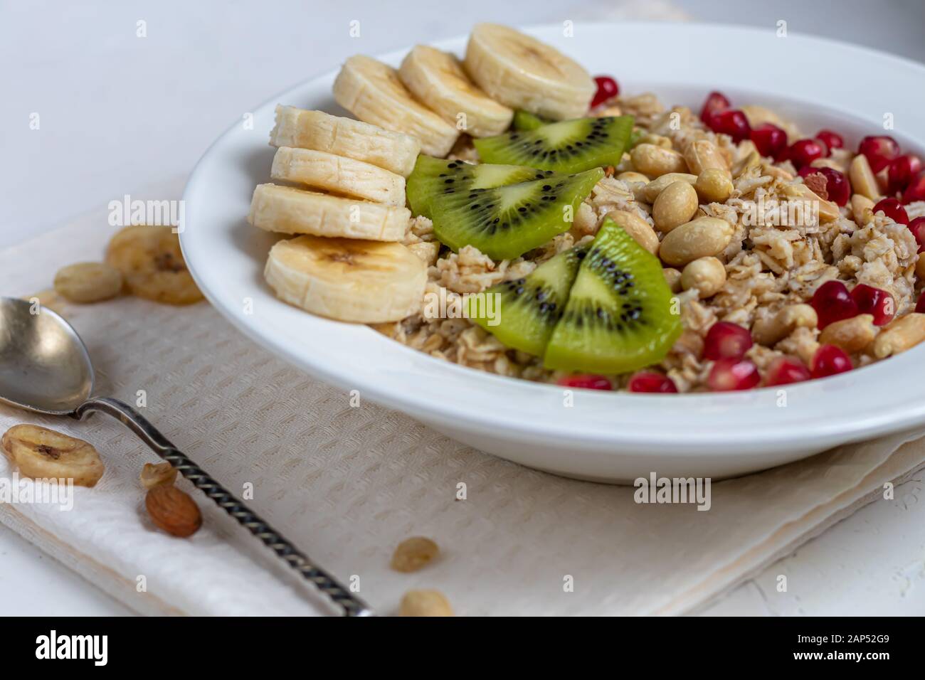 Breakfast consisting of oatmeal, nuts and fruits. Kiwi, banana ...