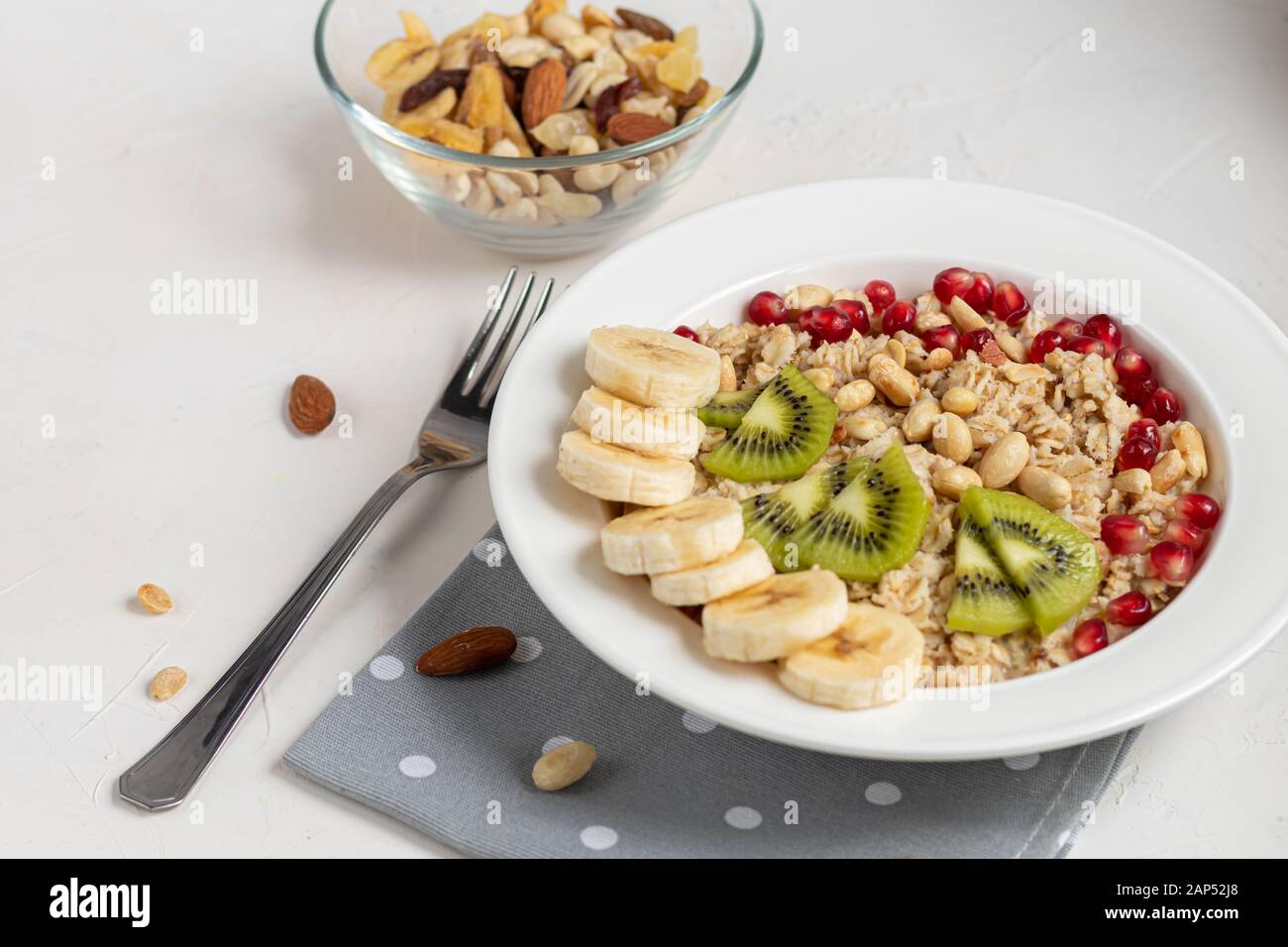 Breakfast consisting of oatmeal, nuts and fruits. Kiwi, banana ...