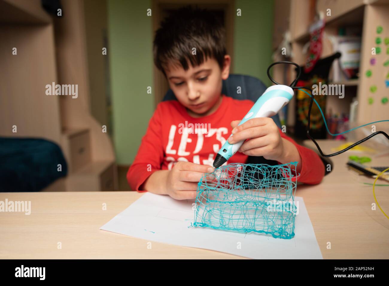 Boy creating volume plastic figure with 3D pen. Selective focus ...
