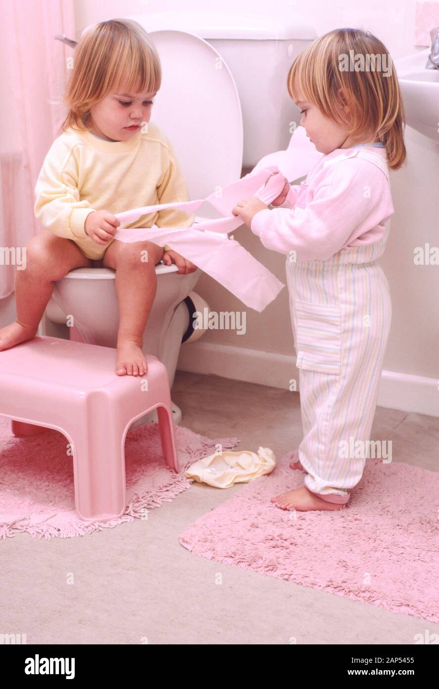 twin girls toilet training, sitting on the loo unrolling toilet paper ...