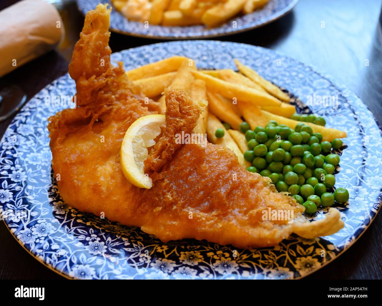 Traditional British food fish and chips served with green peas in pub ...