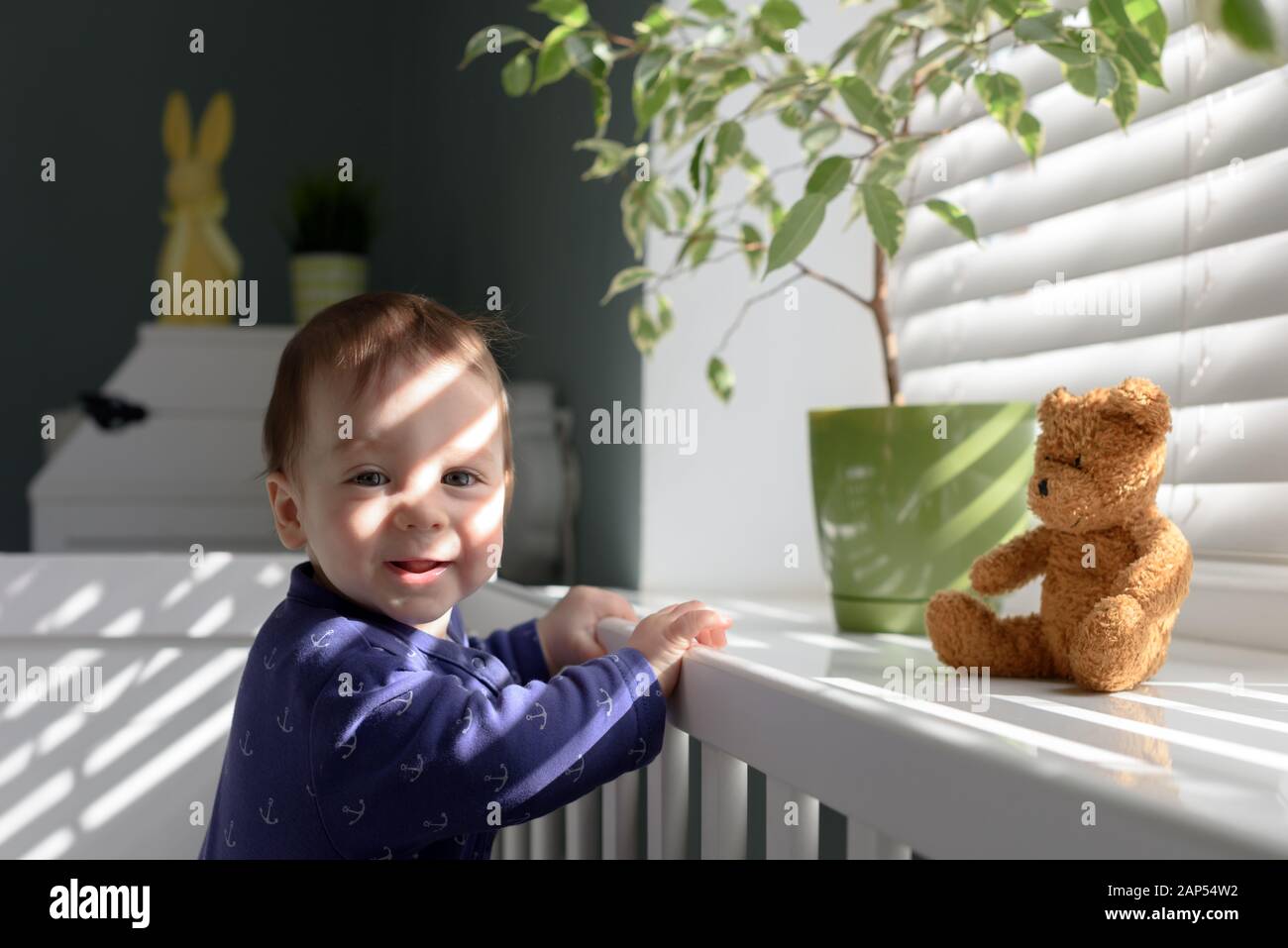 Smiling kid near window on white bed in his room. Childhood concept ...