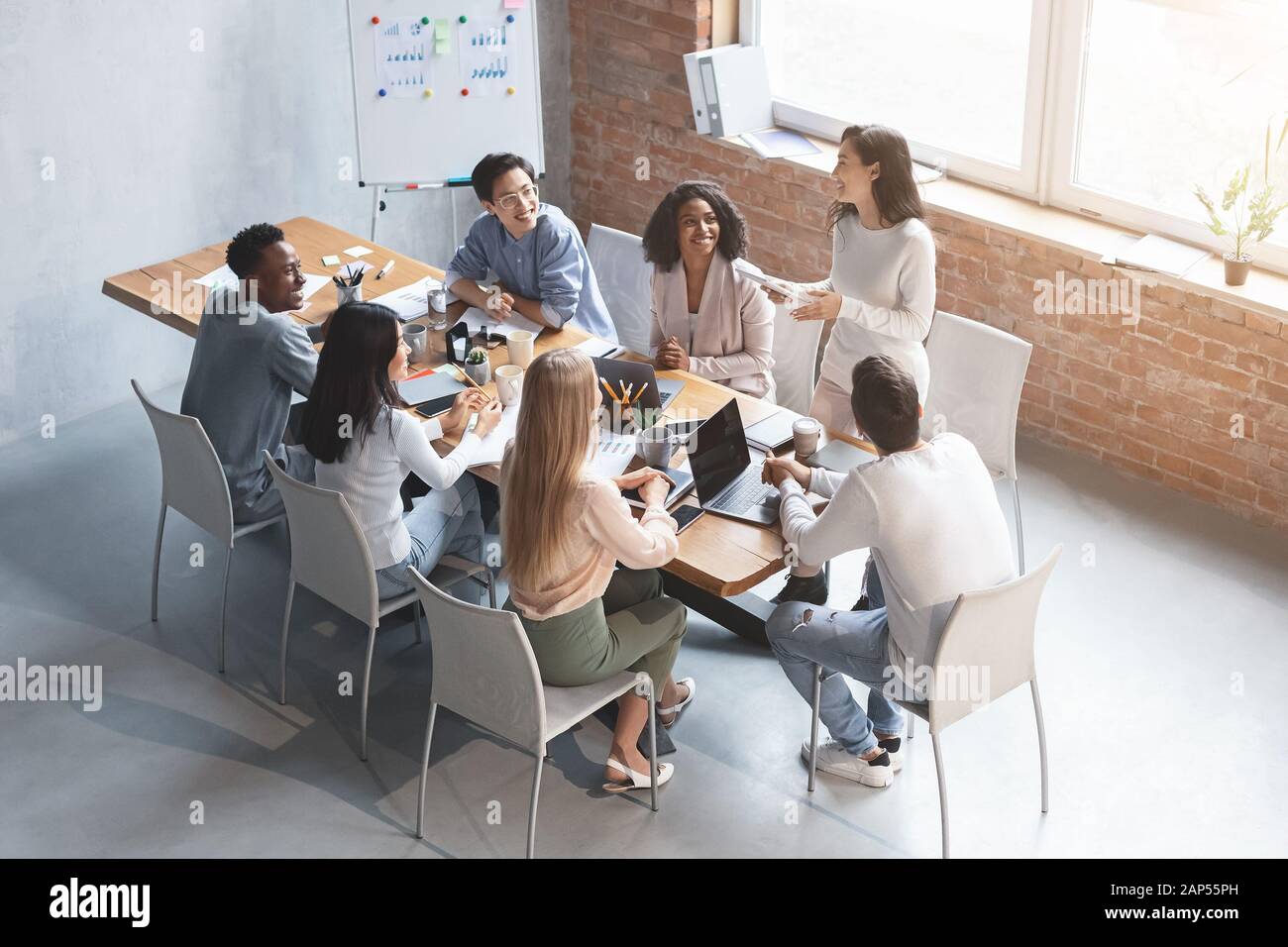 Enthusiastic girl sharing her ideas with cheerful colleagues while ...