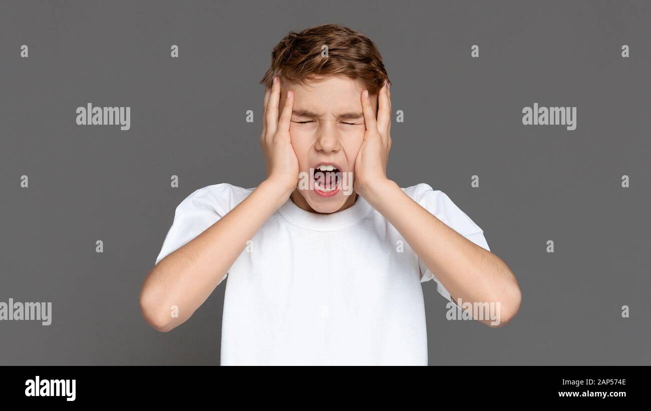 Exhausted teen boy shouting in panic, grey background Stock Photo - Alamy