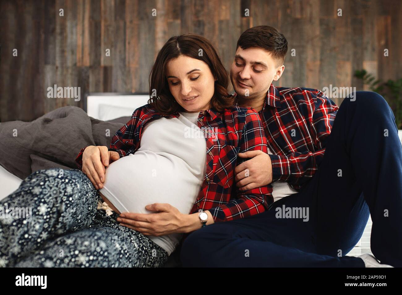 A young married couple awaiting a baby. Beautiful couple lying in the ...